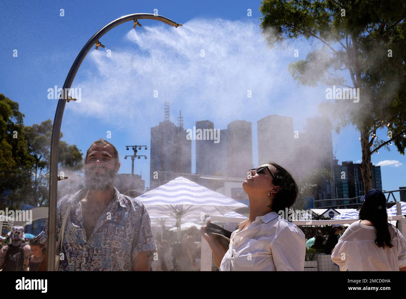 Spectators stand under cooled water misting fans at the Australian Open ...
