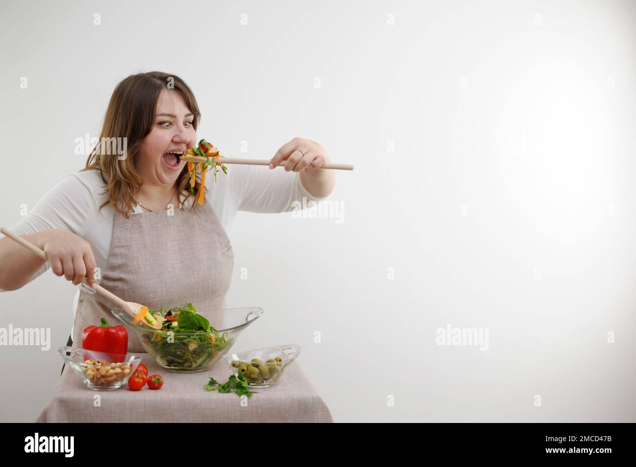 funny cheerful woman eating salad on white background she opens mouth ...