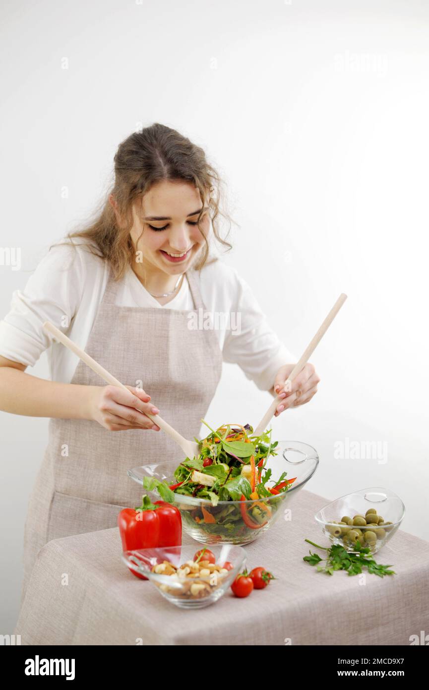 young beautiful teenage girl stirs diligently salad leaned over bowl ...
