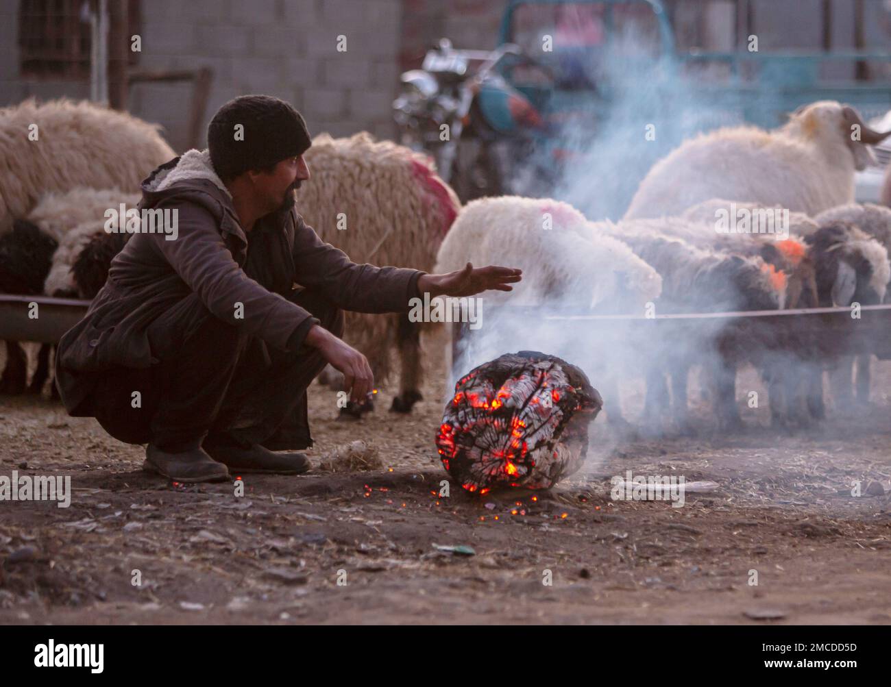 An Iraqi shepherd Mohammed Khader, warms himself by a fire during a ...