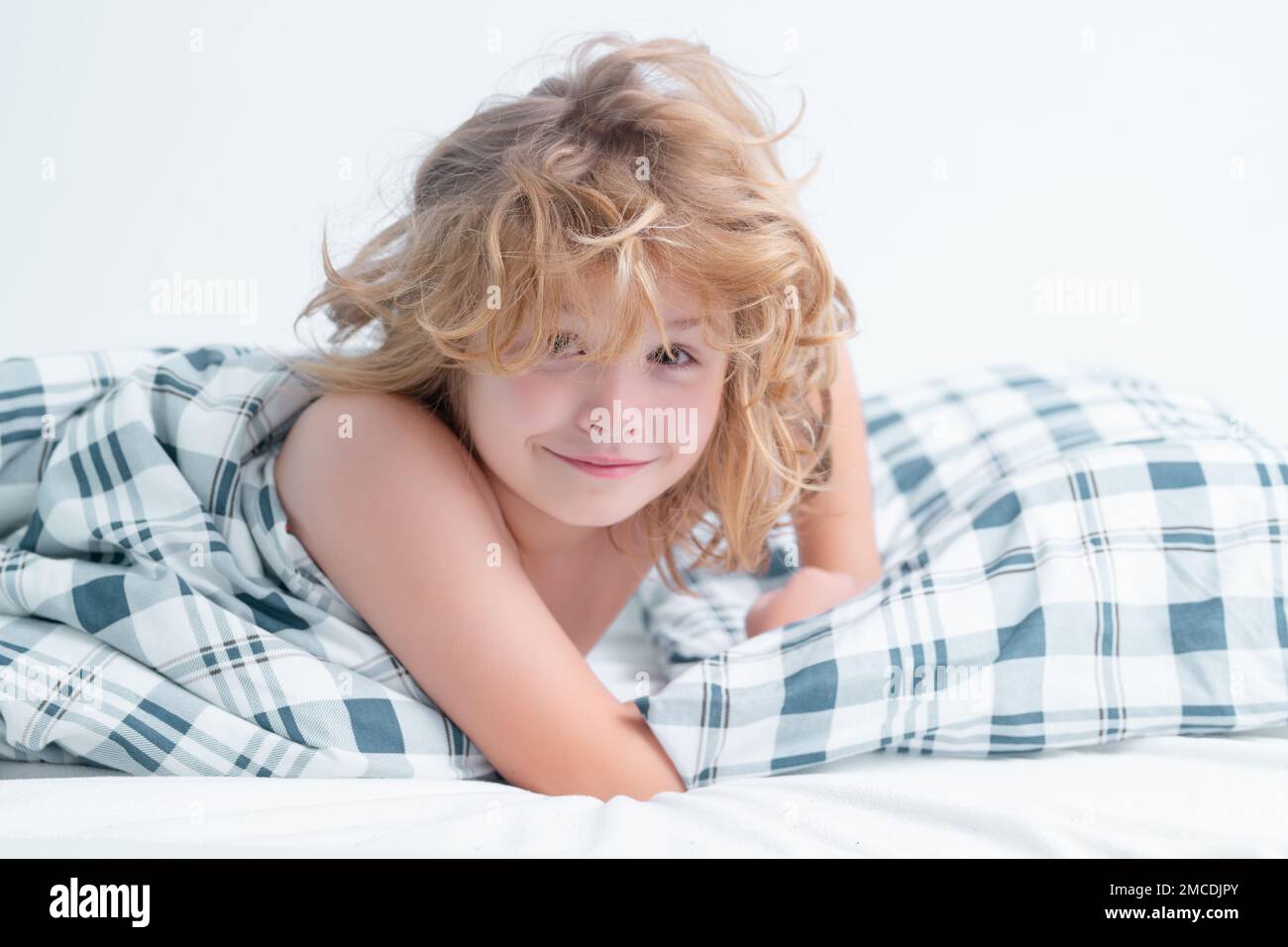 Child wakes up in the morning in the bedroom. Cute little boy waking up in bed. Healthy sleeping ...