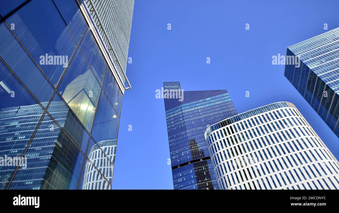 Bottom view of modern skyscraper in business district against blue sky ...