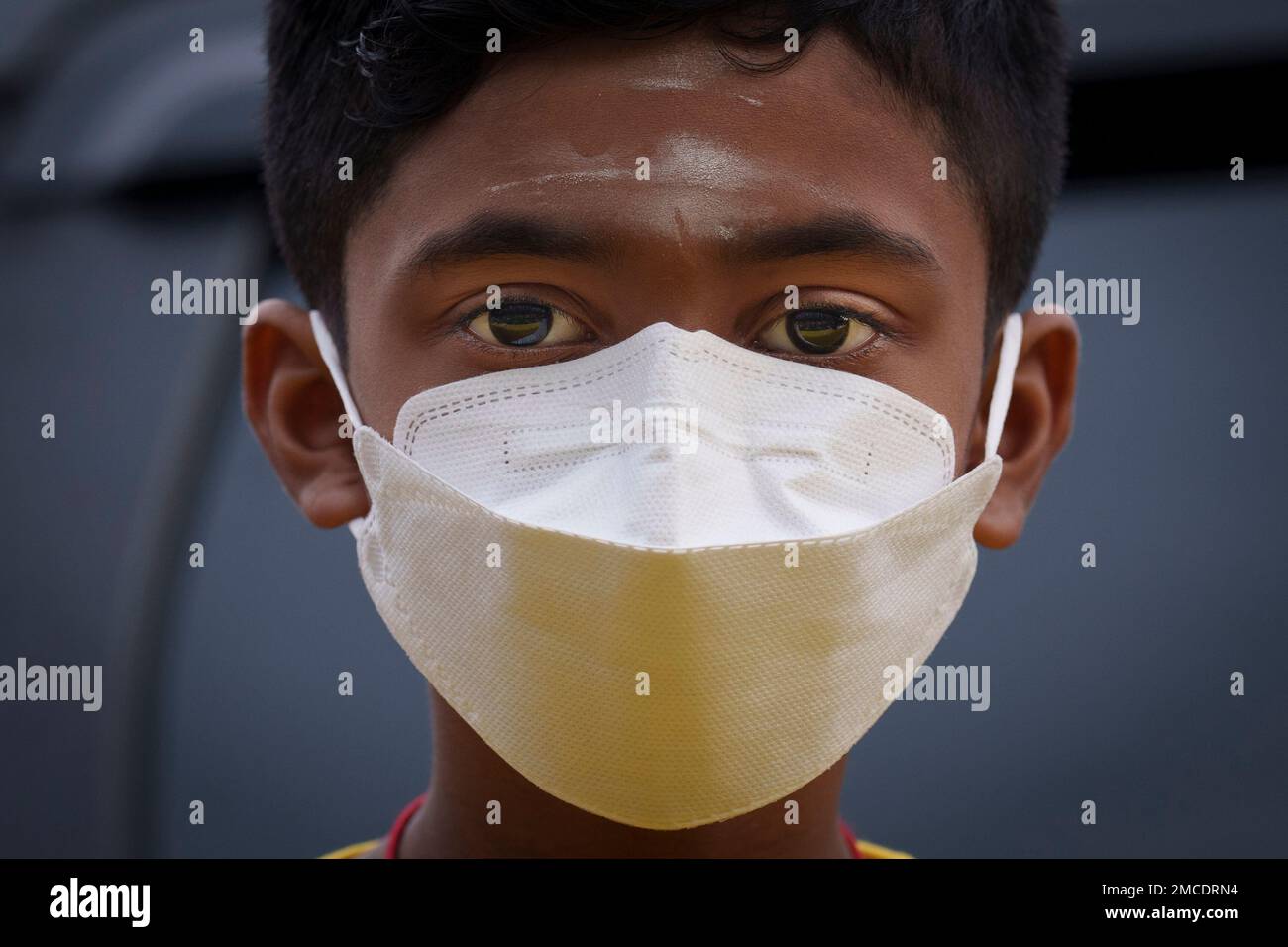 A Hindu boy wearing a face mask looks on in a procession during the ...