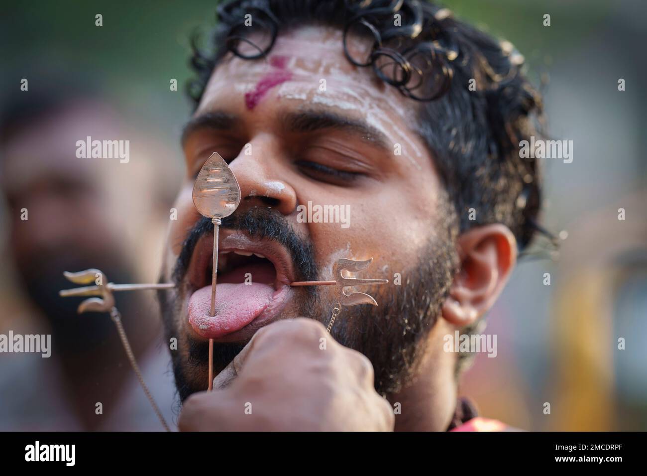 A Hindu devotee gets his tongue pierced with a metal rod during the ...