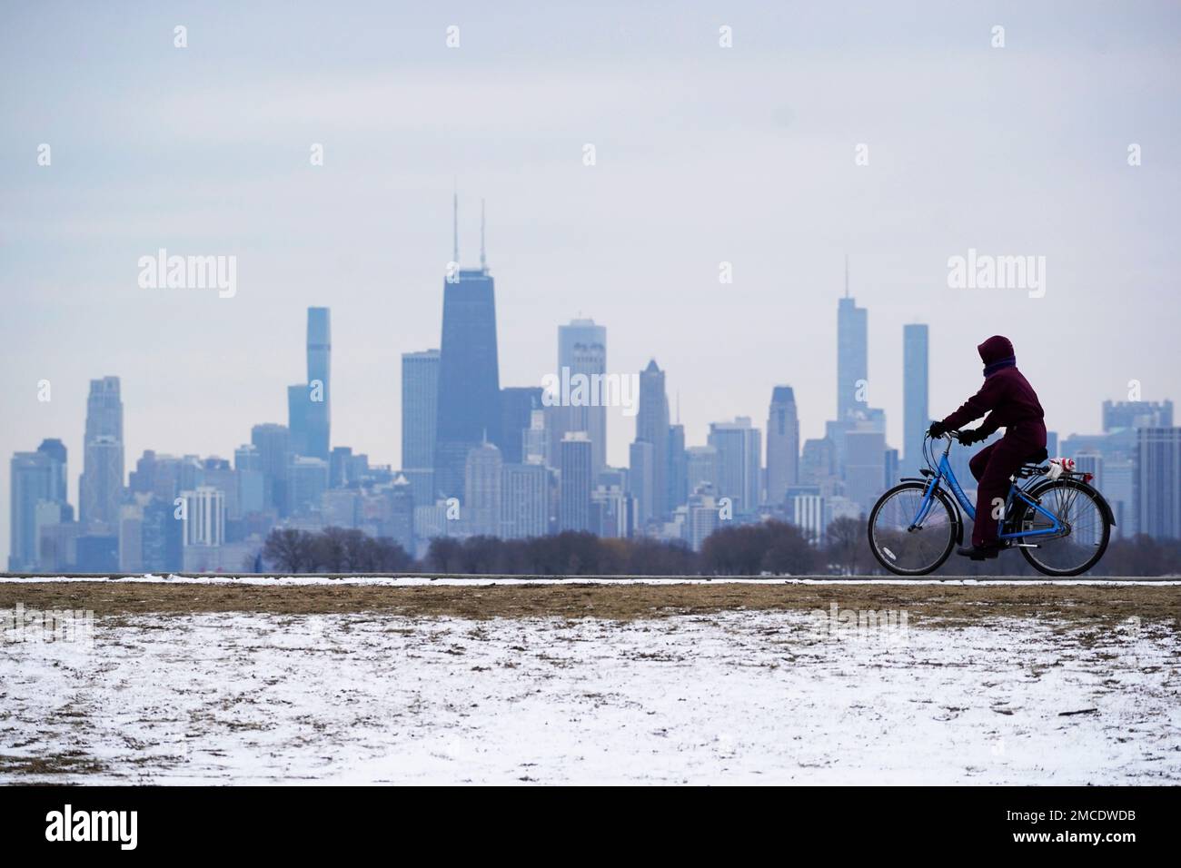 A man rides his bicycle near a light dusting of snow at Montrose Beach ...