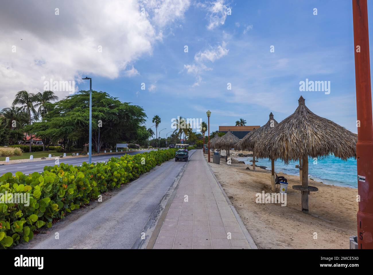 View of electric car driving of on road along sandy beach with sun ...