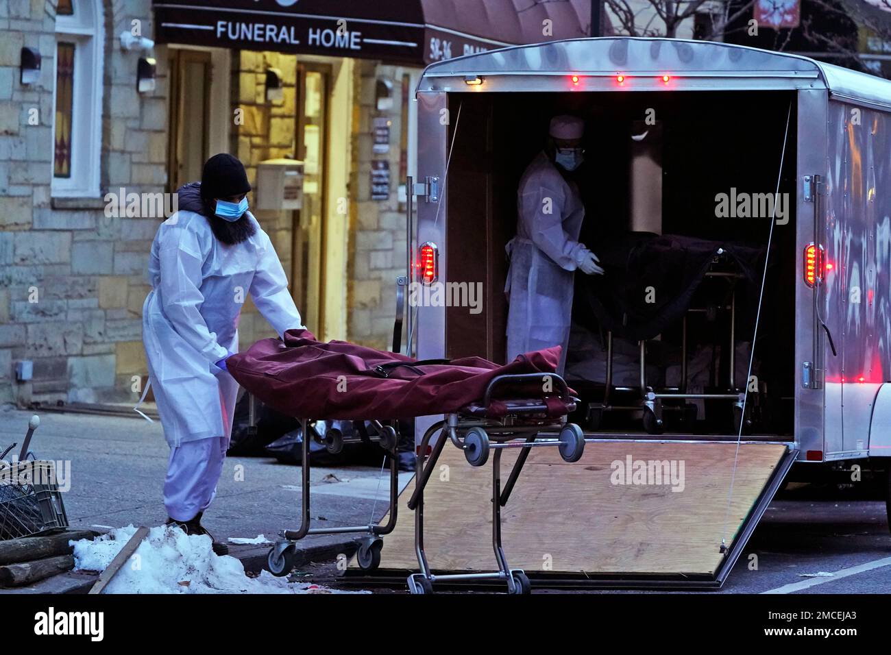 Men unload the bodies of victims of a building fire from a trailer into ...