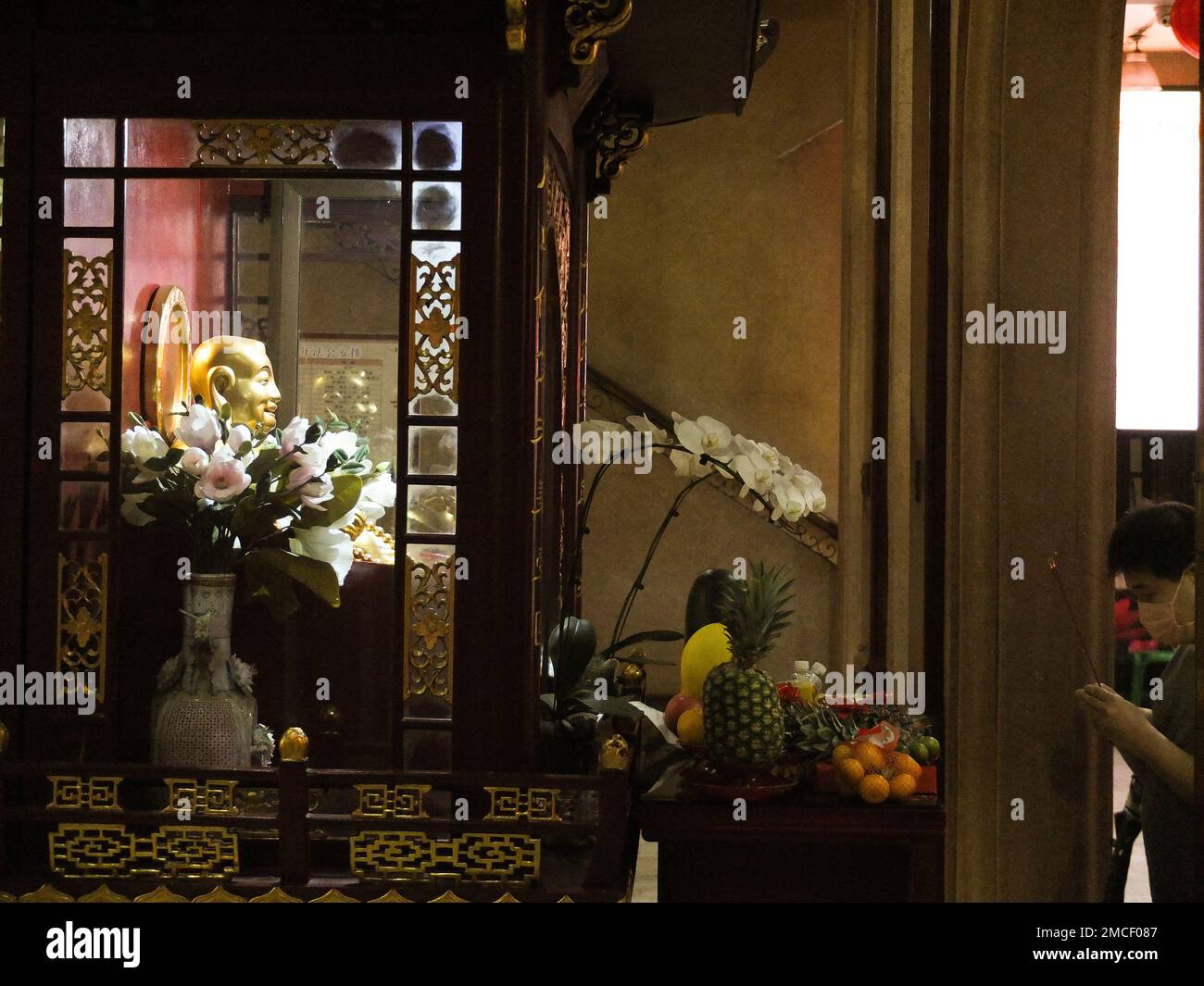 A Chinese man lights an incense and offers prayers to Buddha at Seng ...