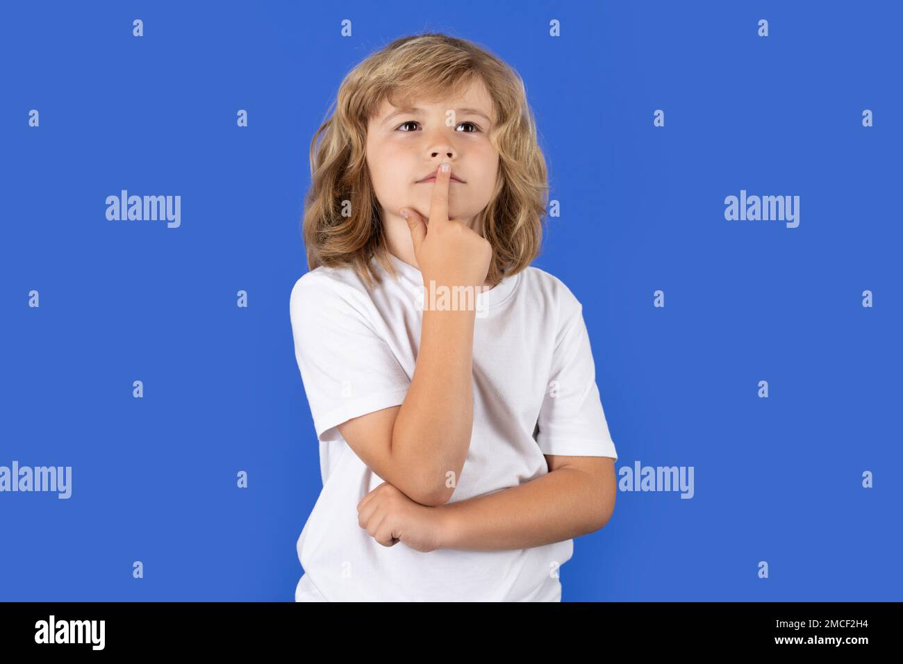 Serious little child thinking on blue isolated background. Think and ...