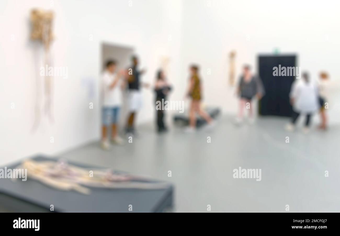 Spectator looking at paintings and sculpture in Art exhibition gallery ...