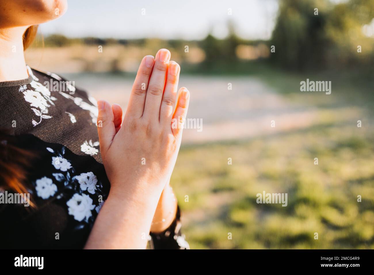 Unrecognizable believer person with praying hands at sunset in the ...