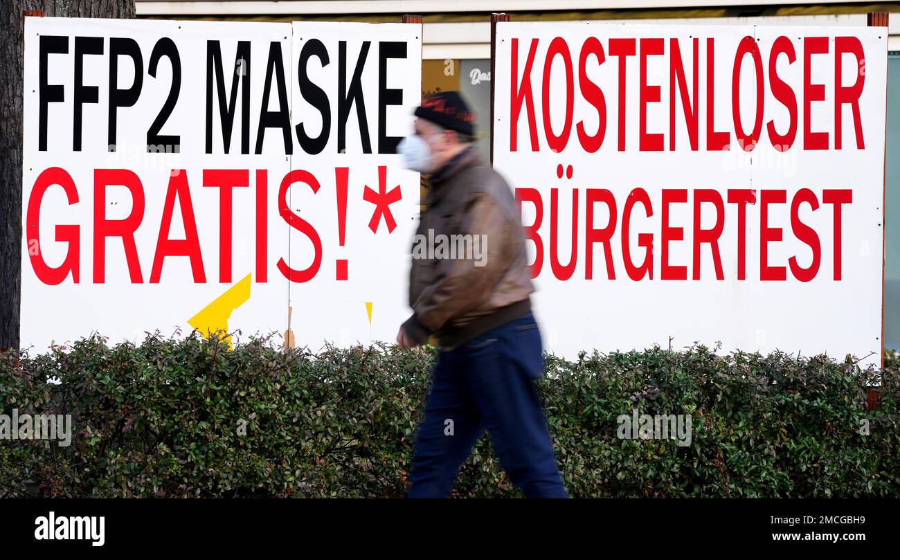 A person walks past advertising boards in front of a Corona Covid-19 ...