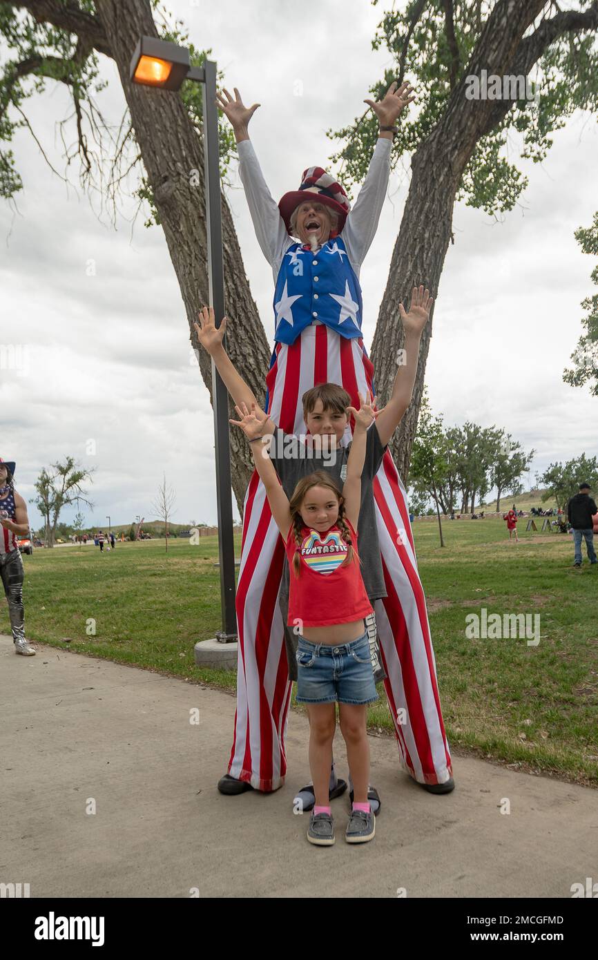 A man on stilts dressed as Uncle Sam poses for a photo with children ...