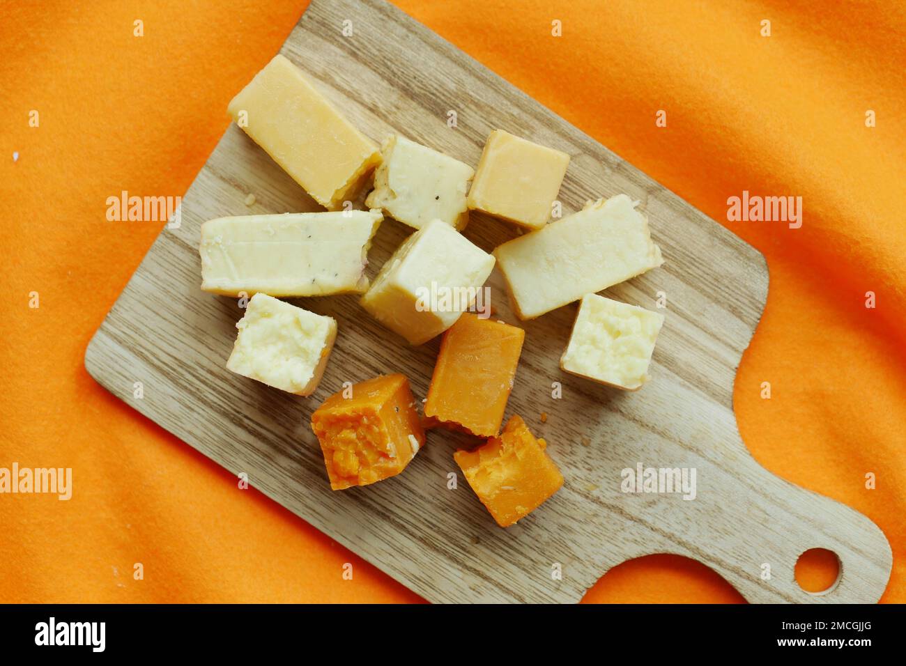 Cheese cubes green, yellow and red color on chopping board Stock Photo ...