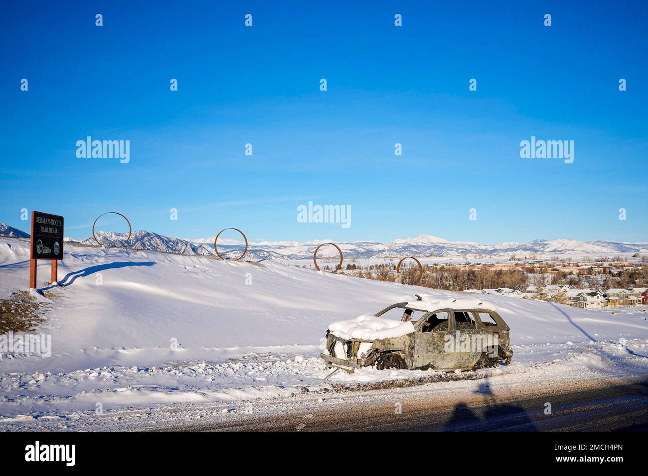 Snow covers the burned remains a car after wildfires ravaged the area ...