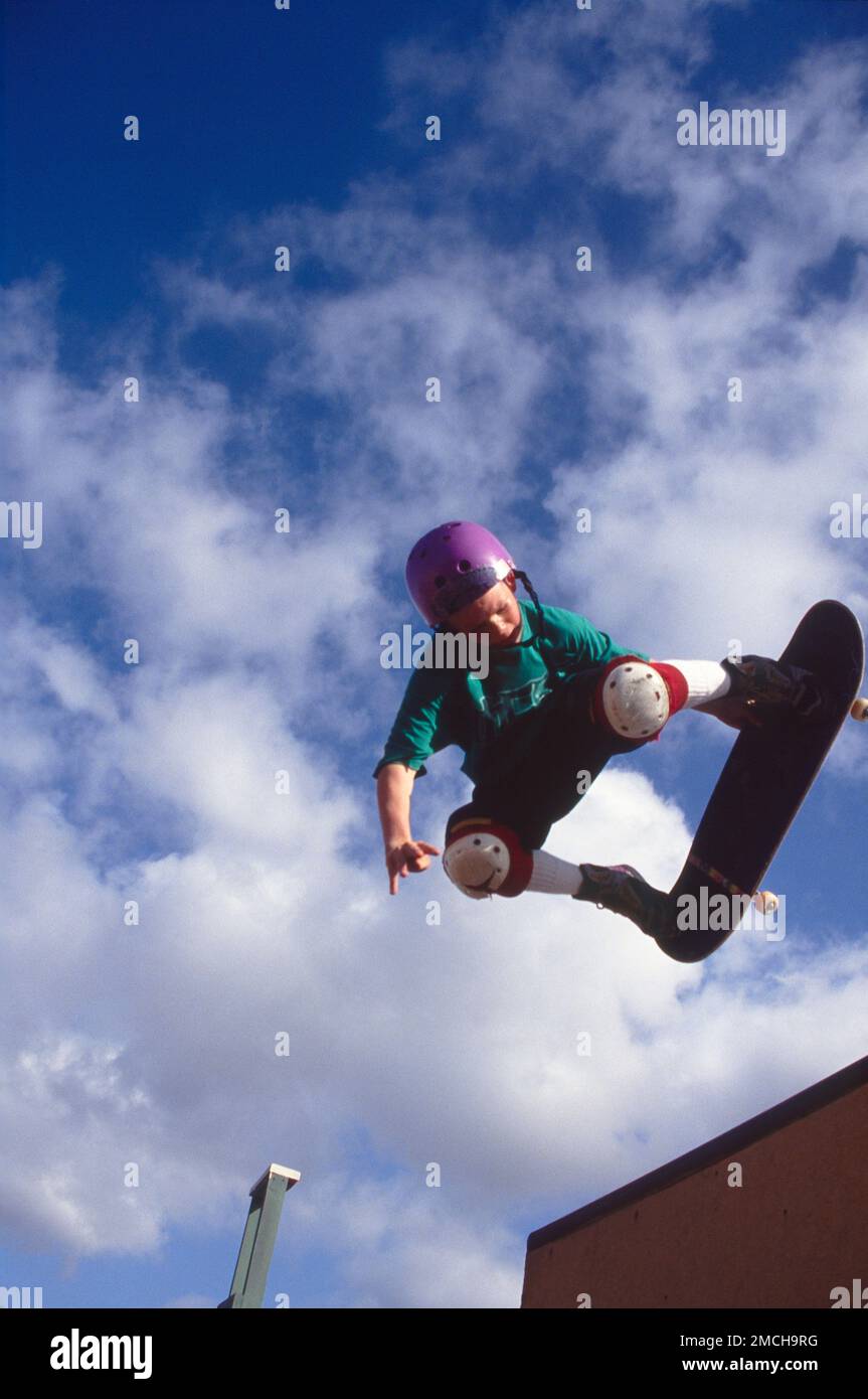 Young boy up in the air on a skateboard doing a stunt Stock Photo - Alamy
