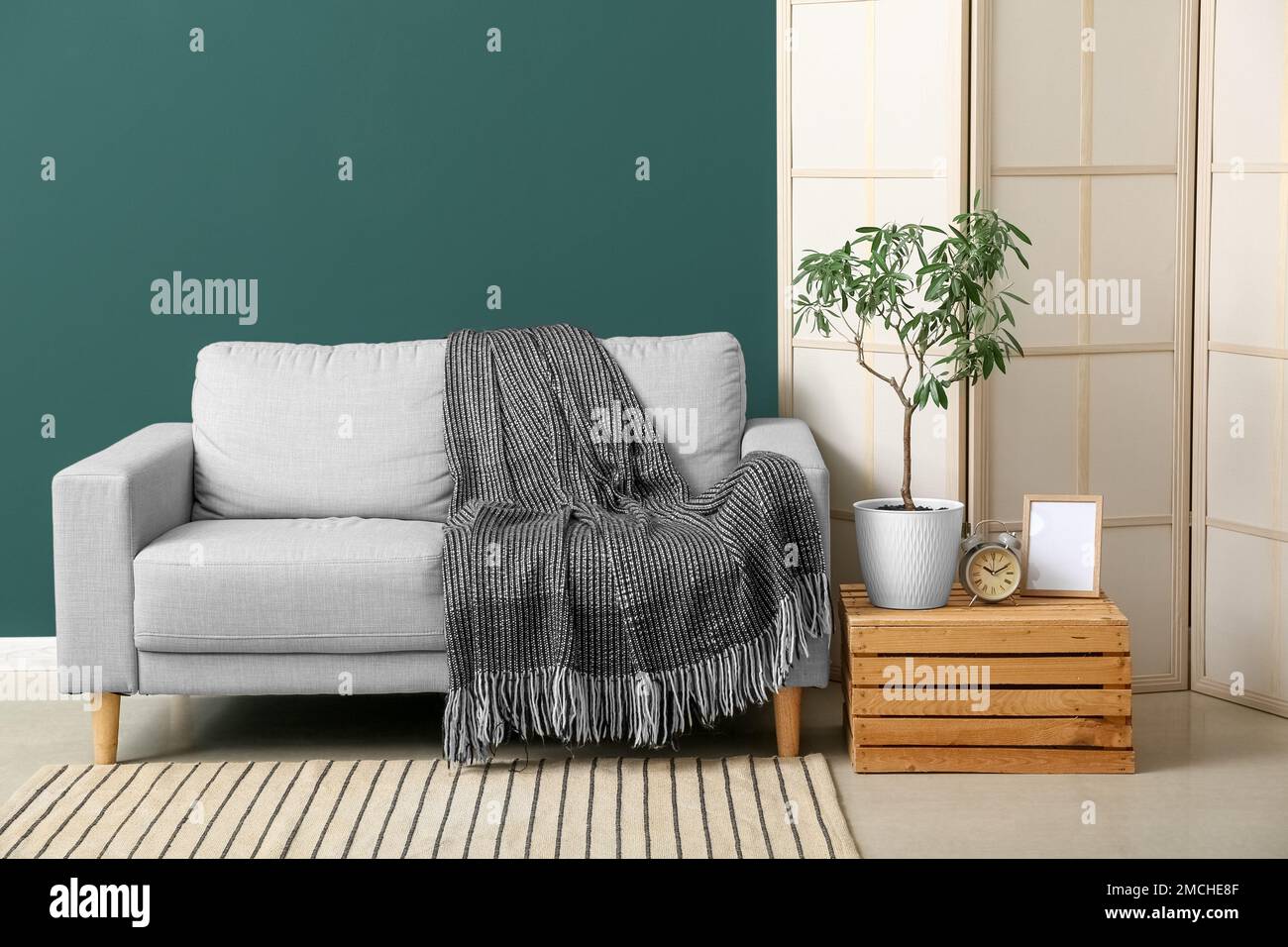 Interior of stylish living room with grey sofa, wooden box and folding ...