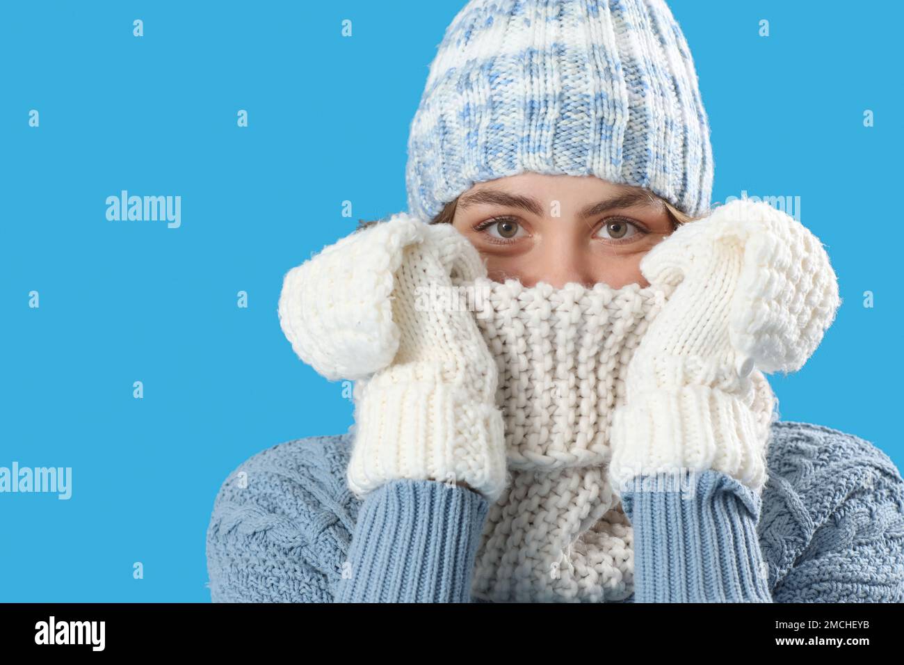 Frozen young woman in winter clothes on blue background, closeup Stock ...