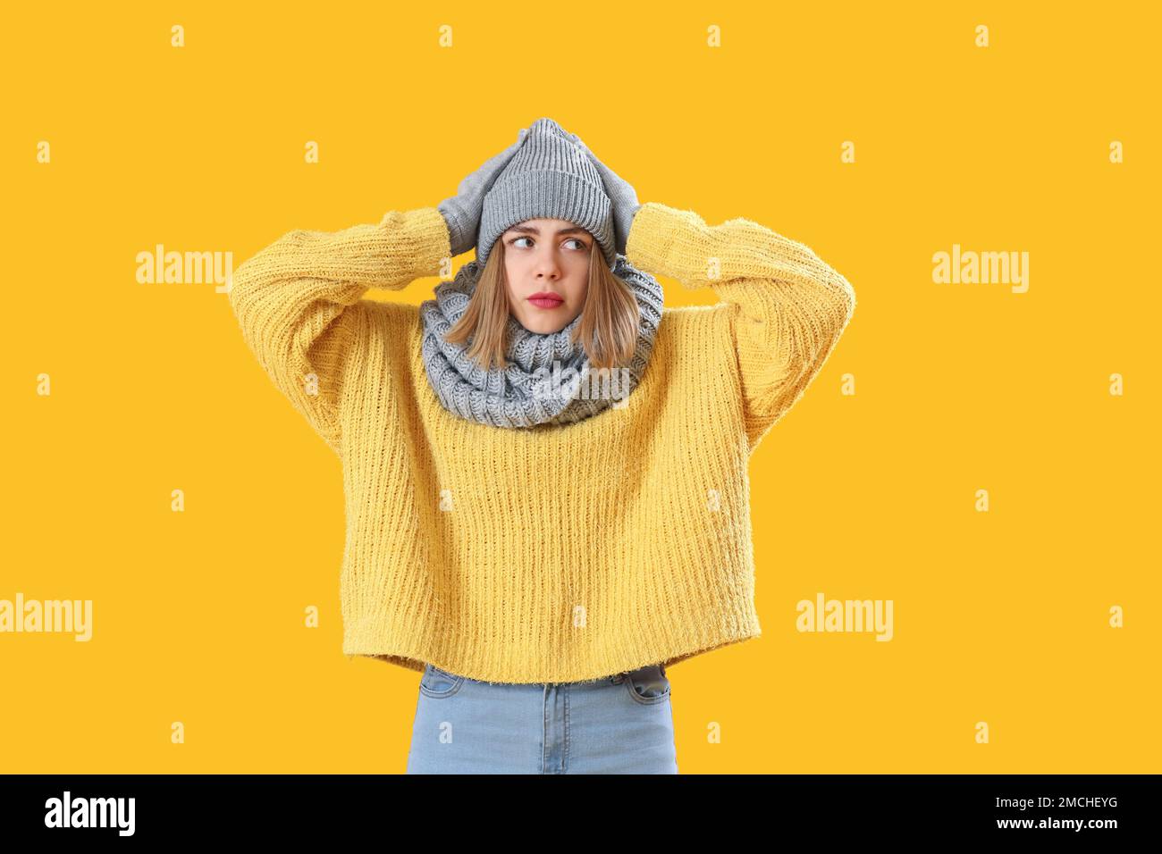 Frozen young woman in winter clothes on yellow background Stock Photo ...