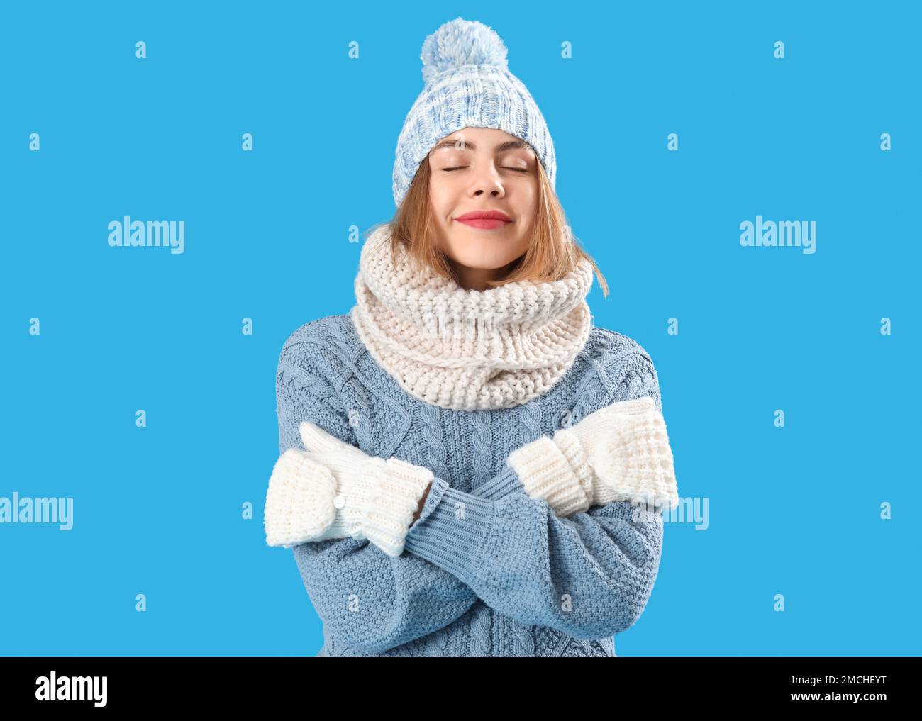 Frozen young woman in winter clothes on blue background Stock Photo - Alamy