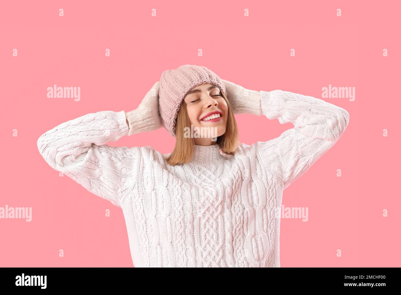 Frozen young woman in winter clothes on pink background Stock Photo - Alamy