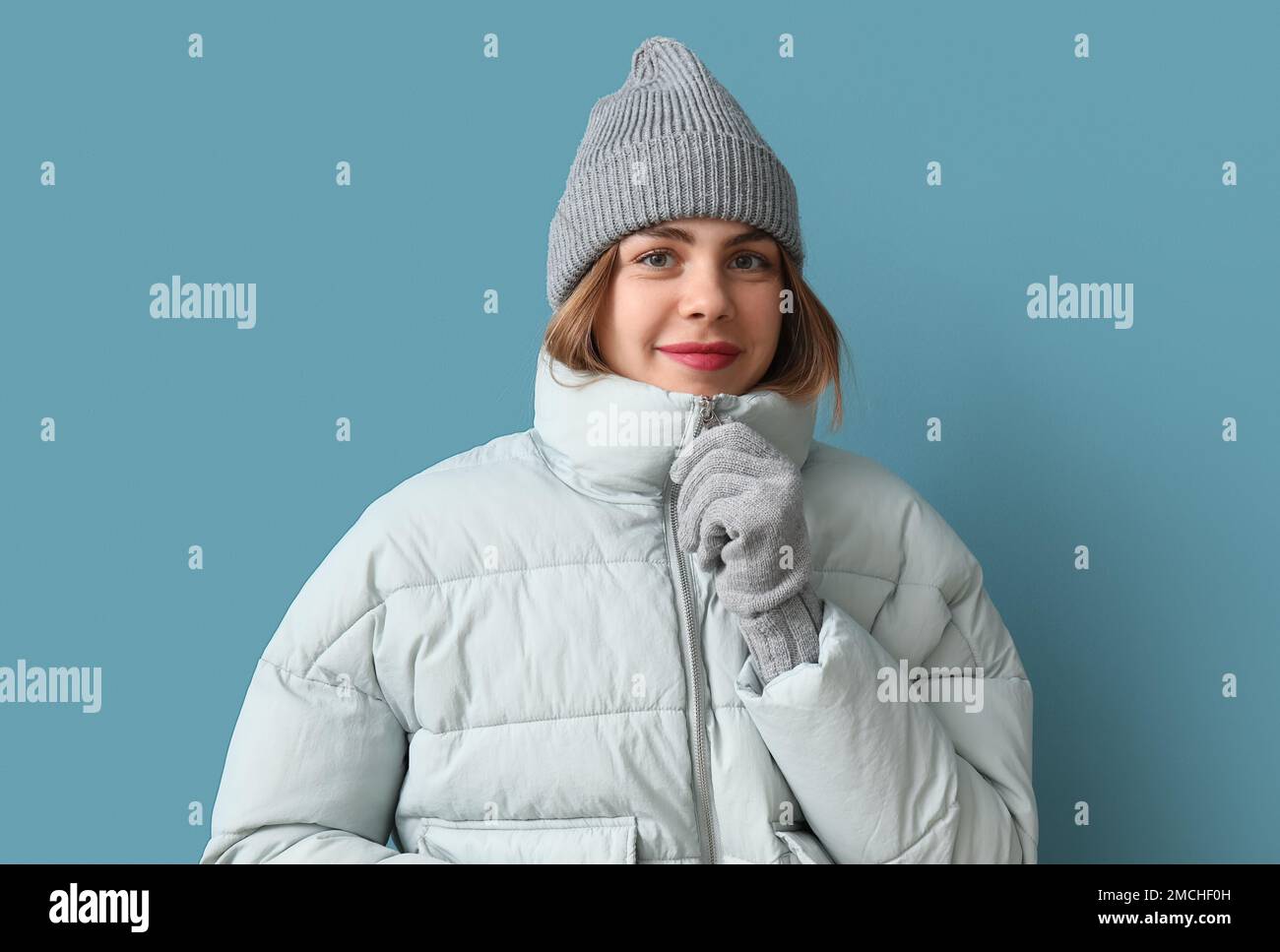 Frozen young woman in winter clothes on blue background Stock Photo - Alamy