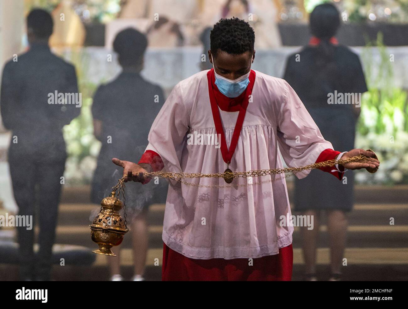 An altar server swings a thurible of burning incense during a memorial ...