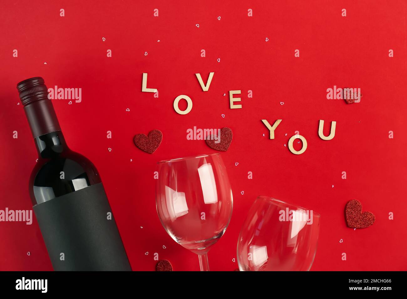 Bottle of wine, words LOVE YOU, glasses and hearts on red background ...