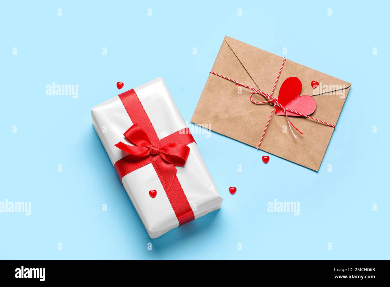 Gift box with beautiful bow, hearts and envelope on blue background ...