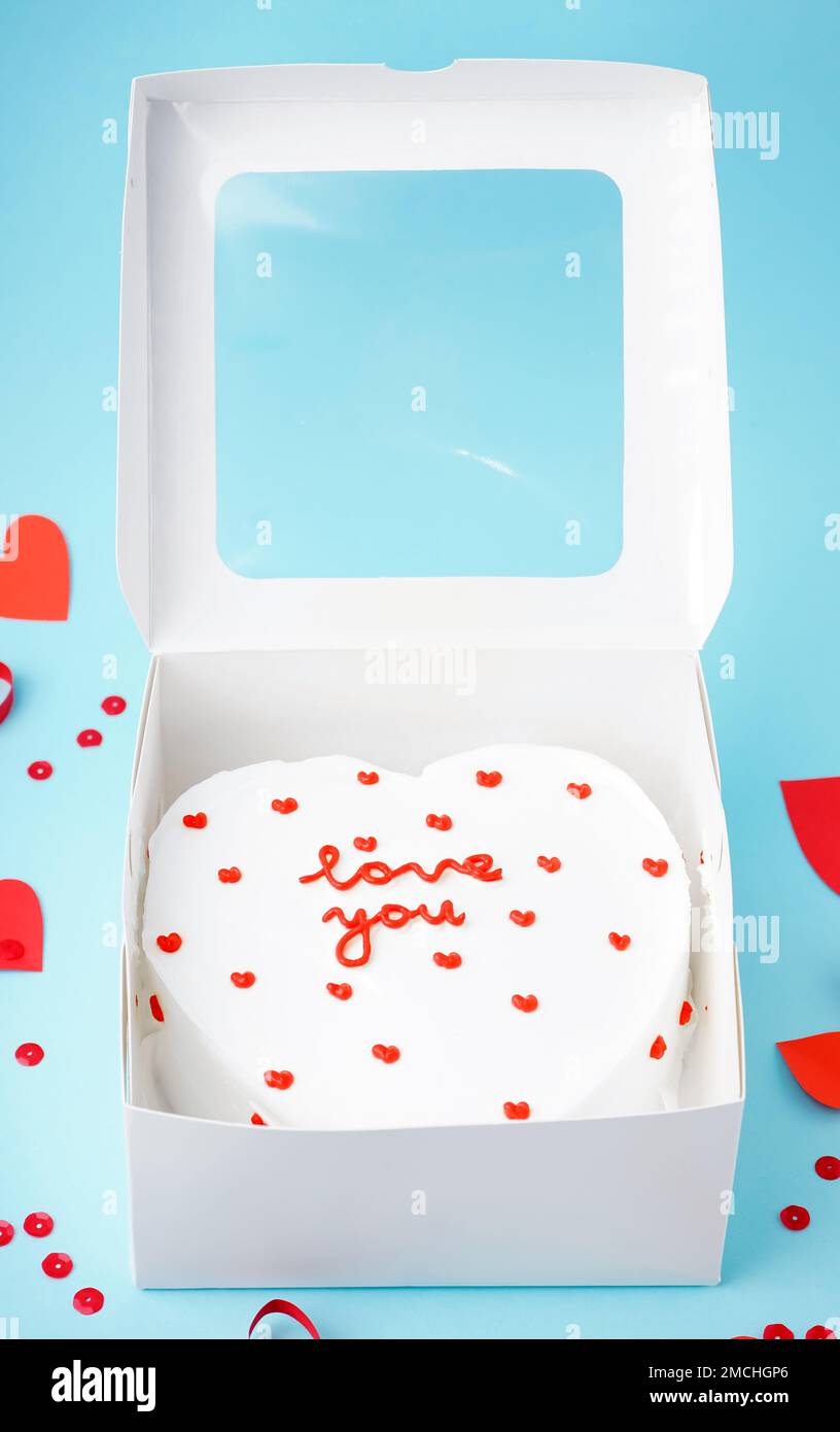 Opened box with heart-shaped bento cake and hearts on blue background ...