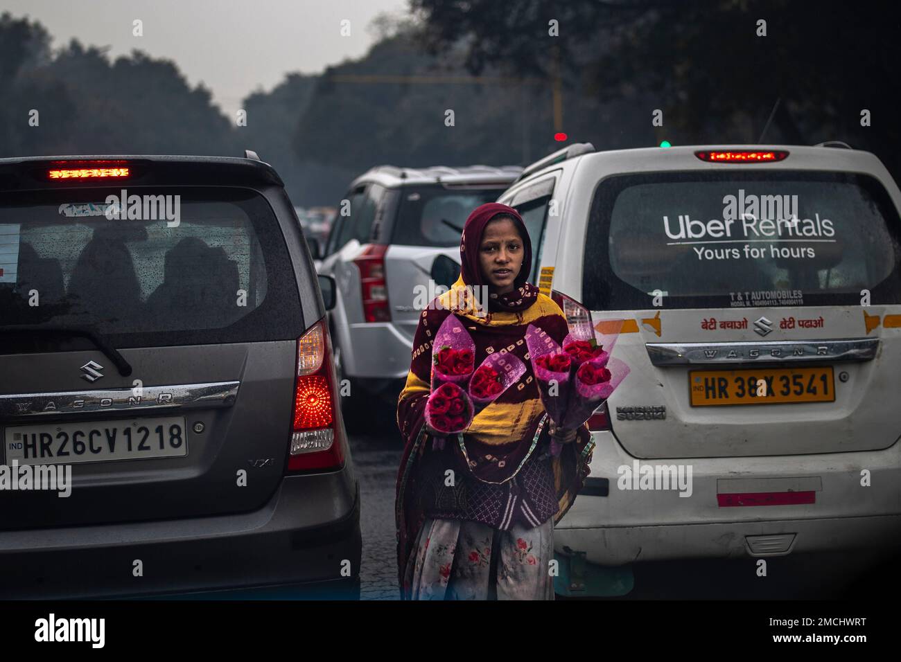 An Indian street vendor sells roses at a traffic intersection as it ...