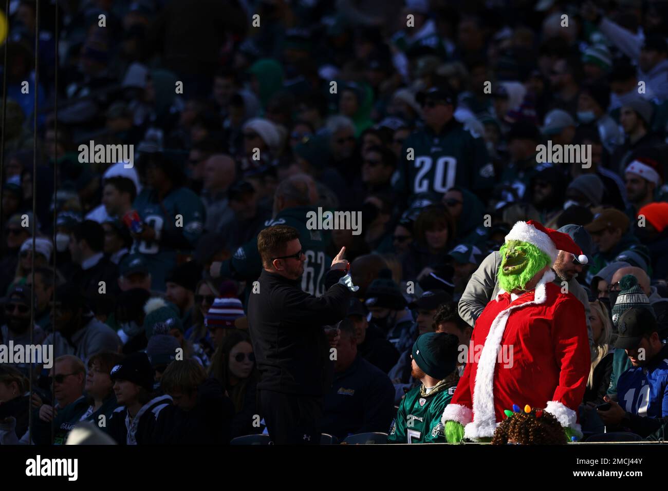 A fan dressed as Santa Grinch watches an NFL football game between the ...