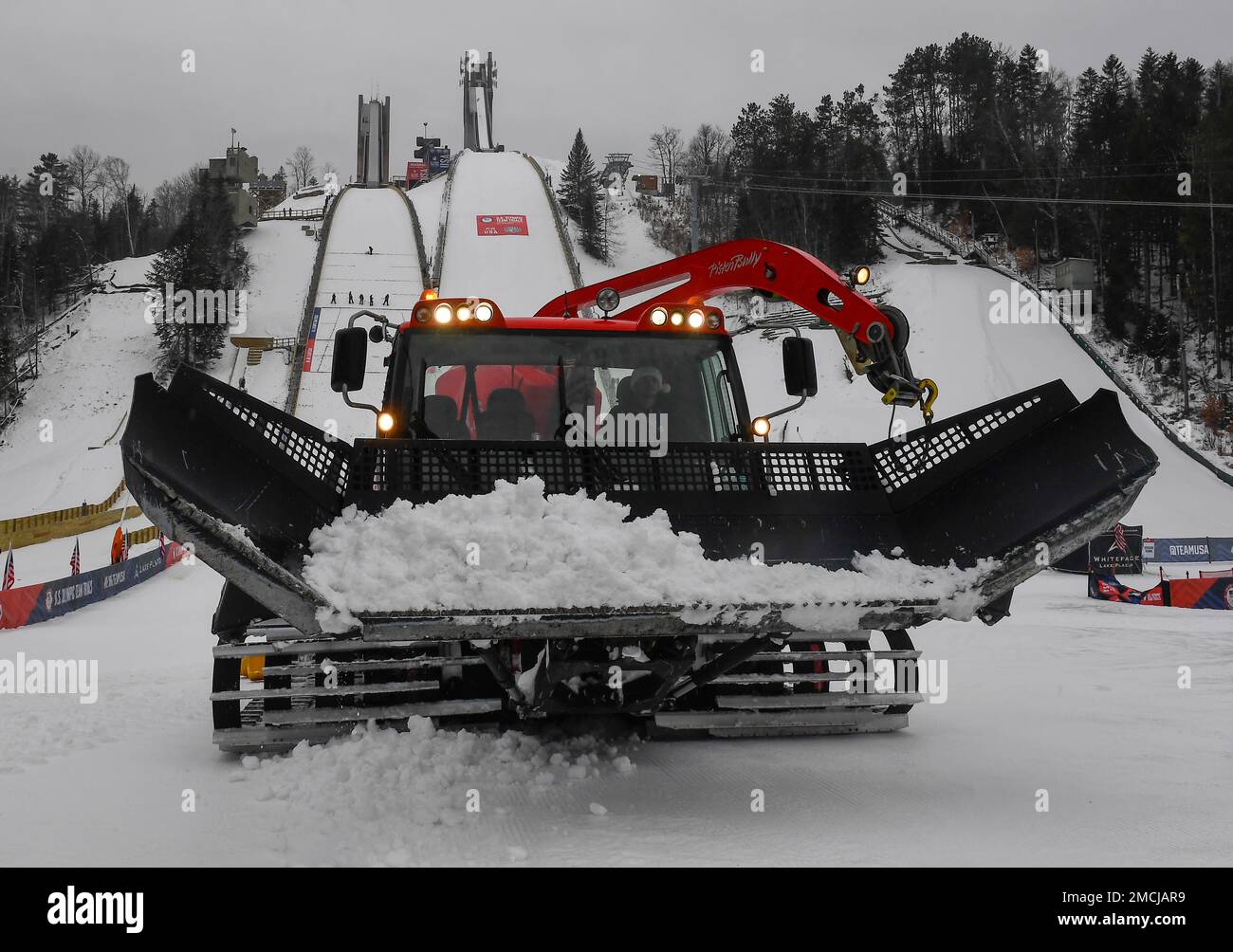 A snowcat operator grooms the landing area before a ski jumping ...
