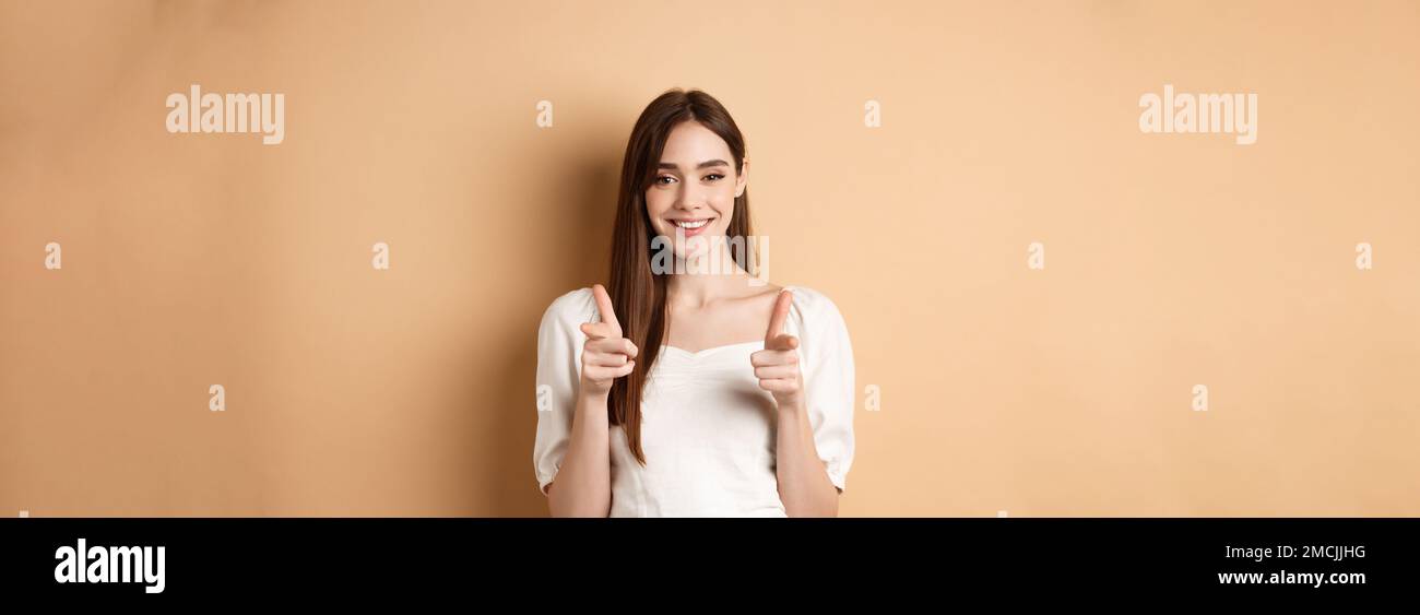 We need you. Smiling young woman pointing fingers at camera to beckon ...
