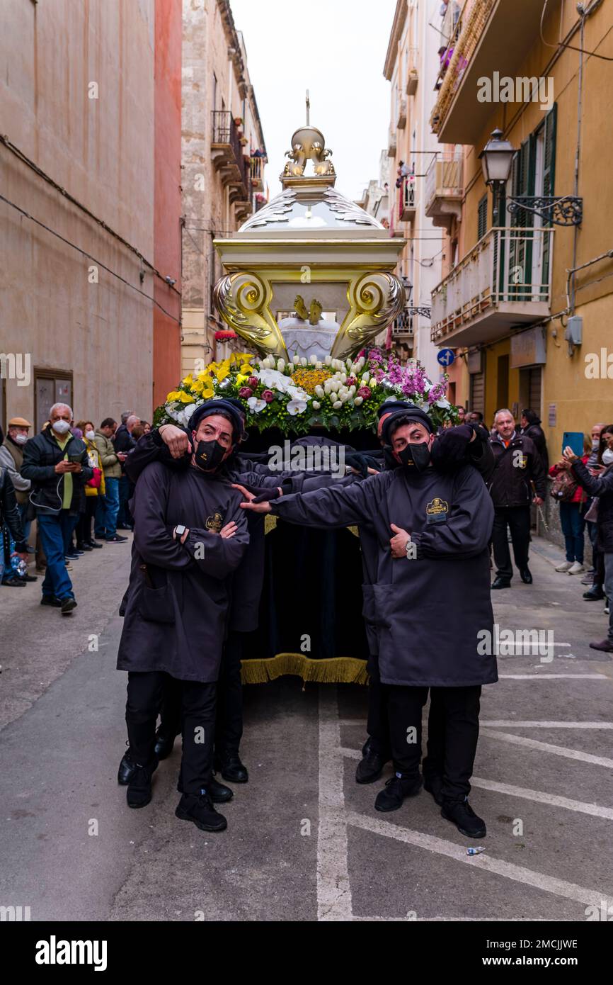 People walk, play music and carry wooden sculptures through the streets ...