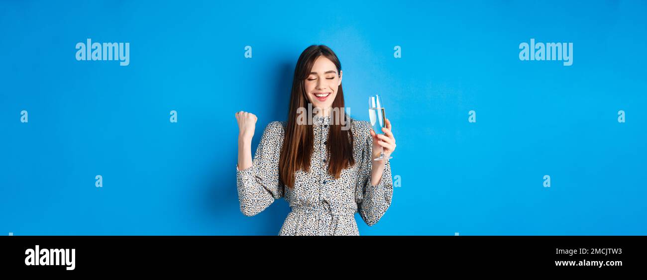 Happy woman celebrating win with glass of champagne, dancing satisfiied ...