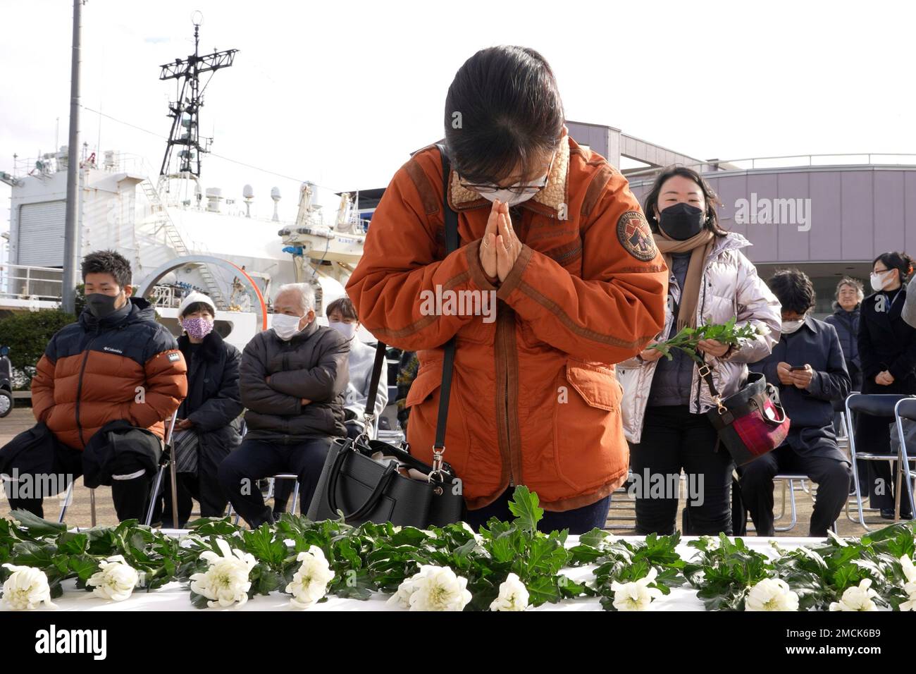 A woman prays after offering flowers for the victims of a resettlement ...
