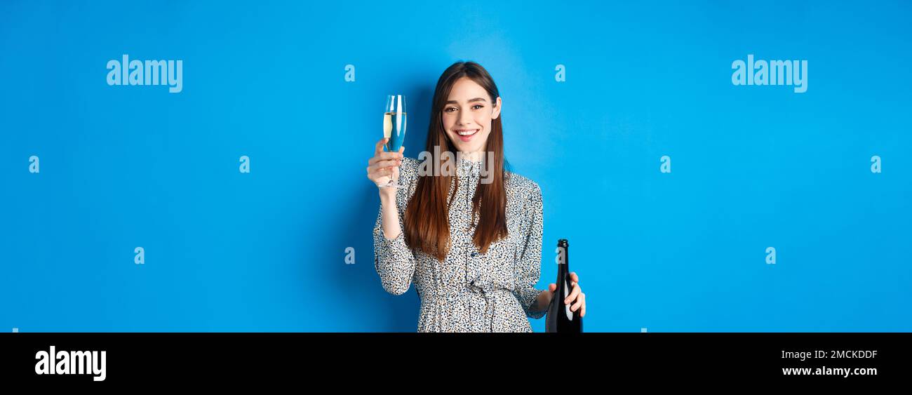 Celebration. Happy young woman in dress raising glass of champagne ...