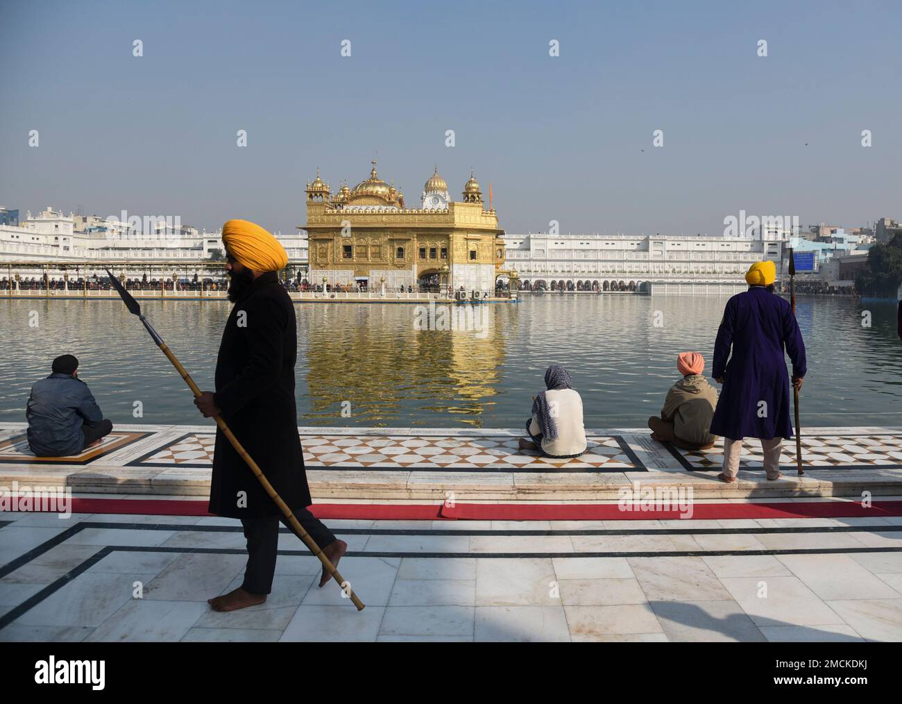 Sikh guards stand holding spears as devotees arrive to worship at the ...
