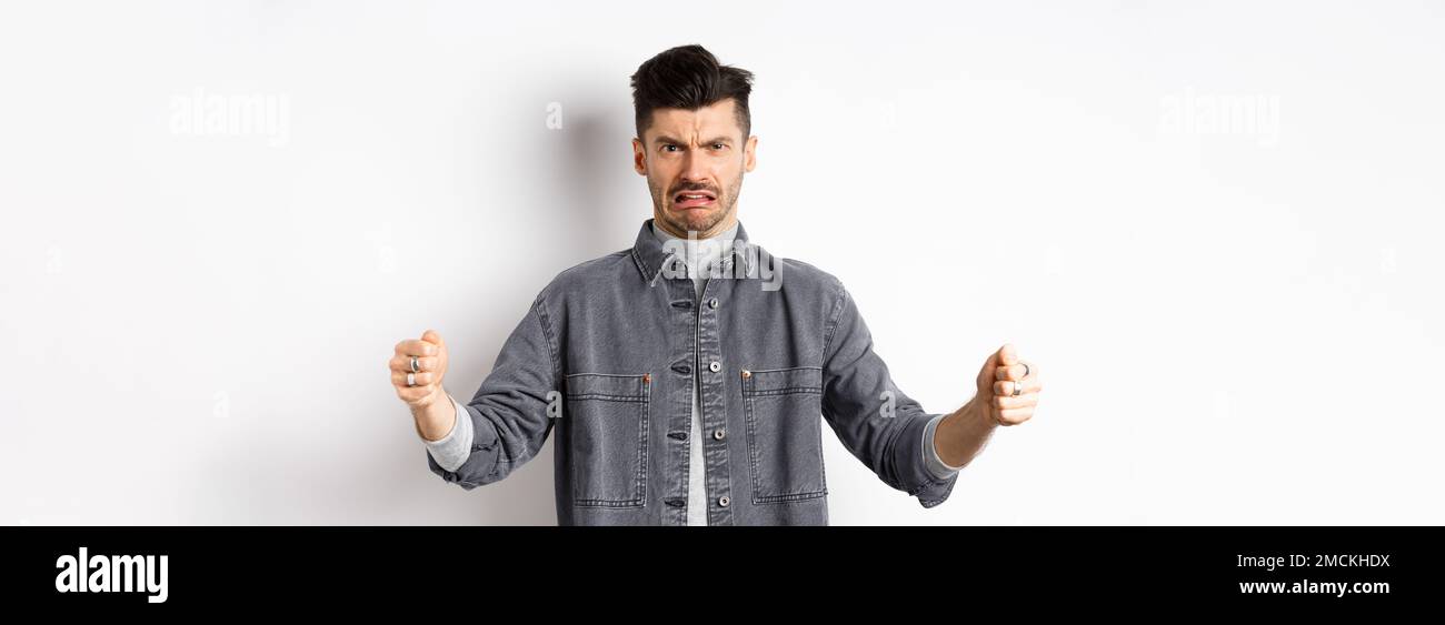 Disgusted guy showing big size object and grimacing from dislike and ...