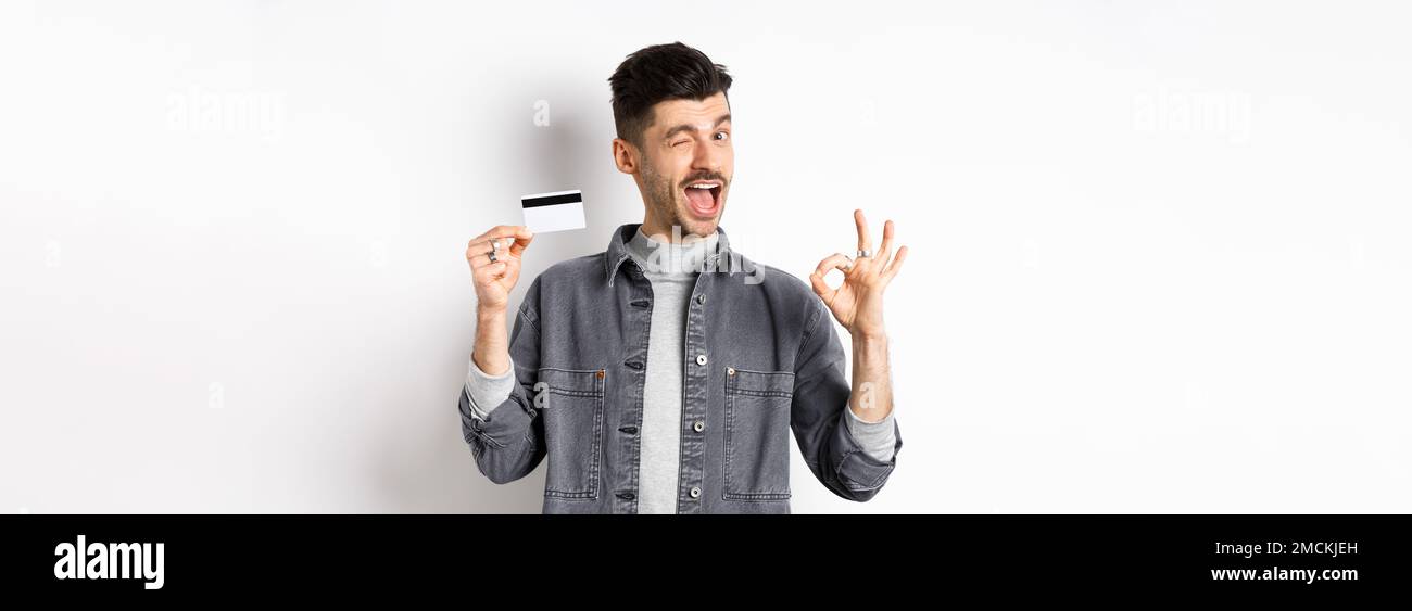 Very good. Smiling guy with plastic credit card showing okay sign ...