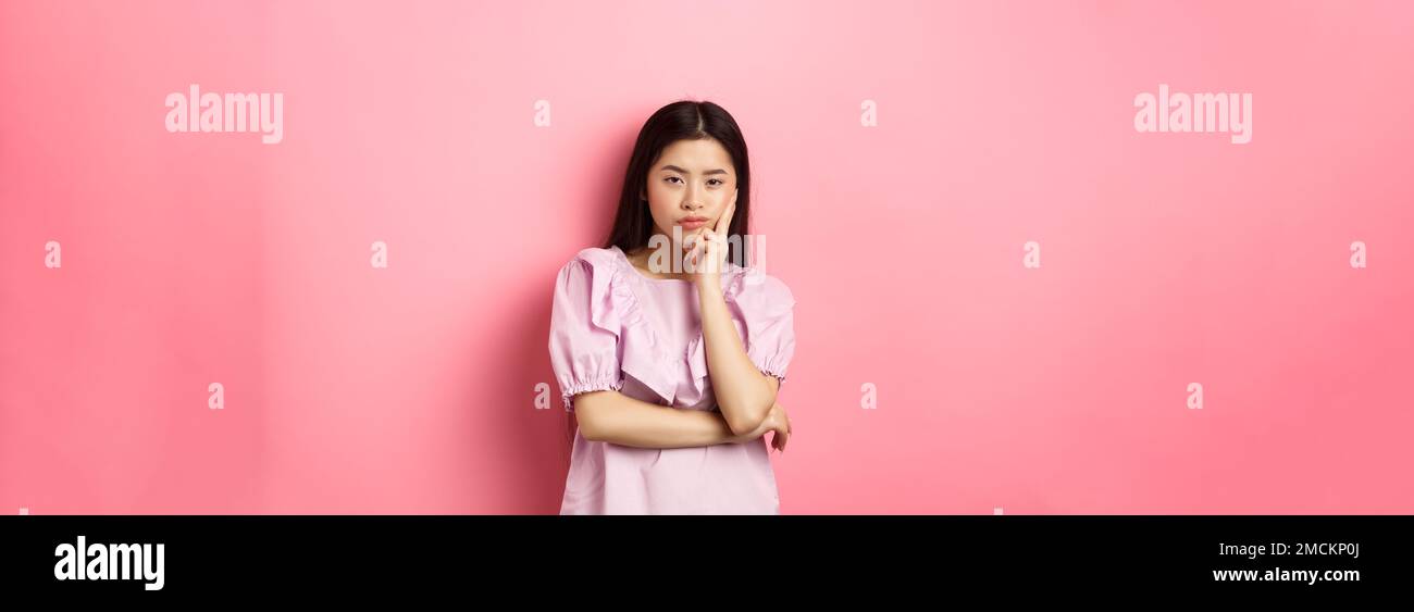 Bored asian teen girl look indifferent at camera, lean face on hand in ...