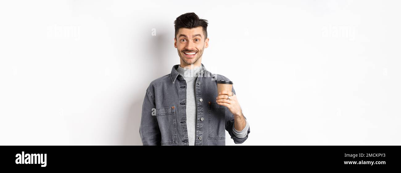 Enthusiastic handsome man holding coffee cup and smiling, drinking good ...
