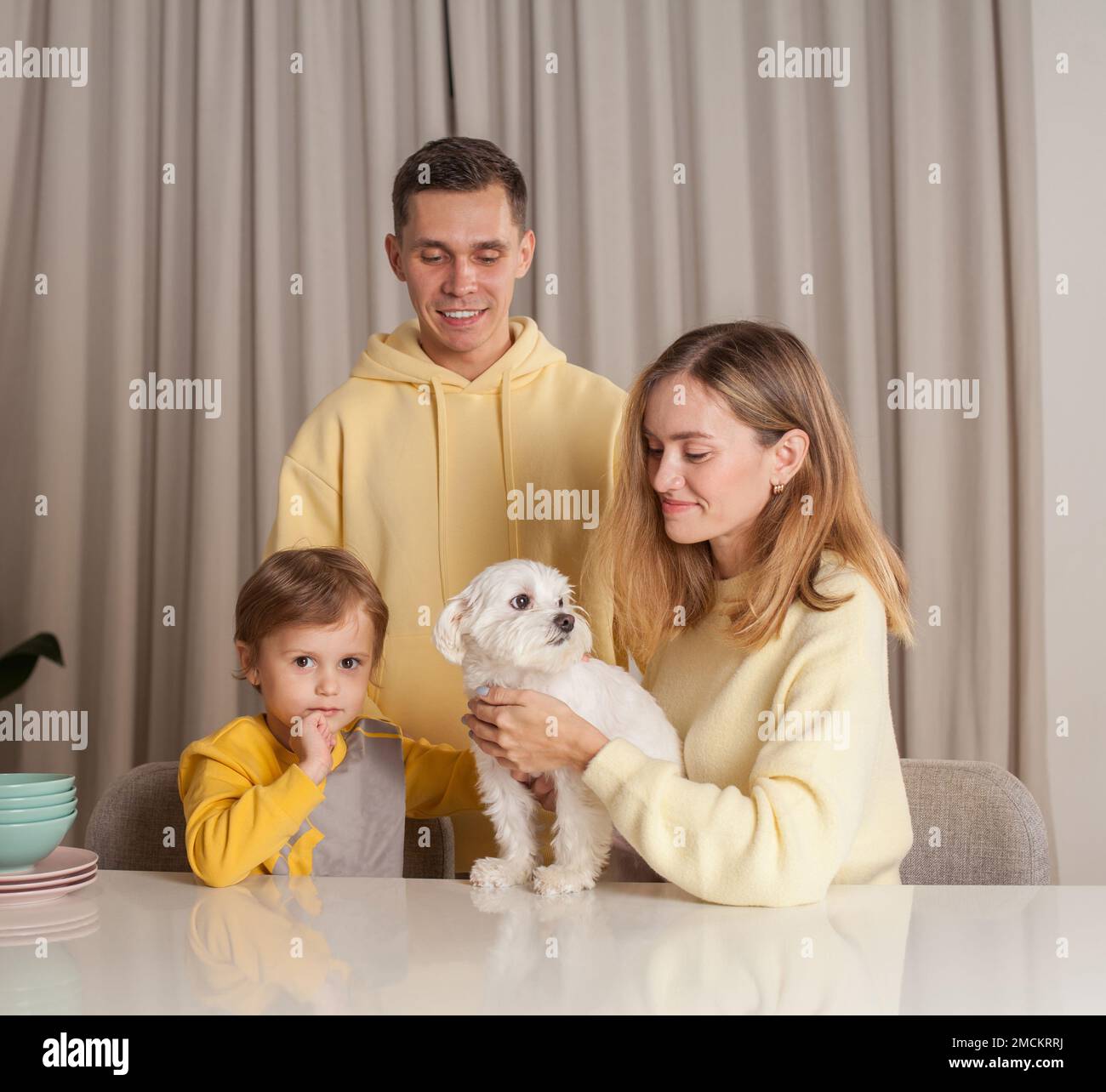 Cute parents in yellow sweaters, happy mother and father with child son ...
