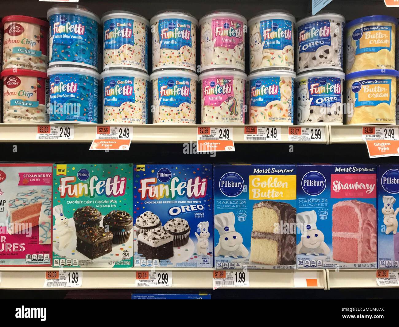 A variety of Pillsbury boxed cake mixes and frosting appear on a shelf ...