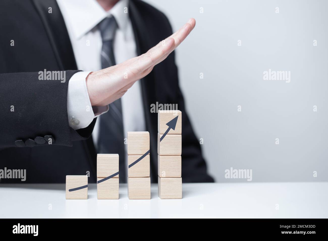 Wooden blocks with black arrows icons, hand in suit pointing up ...