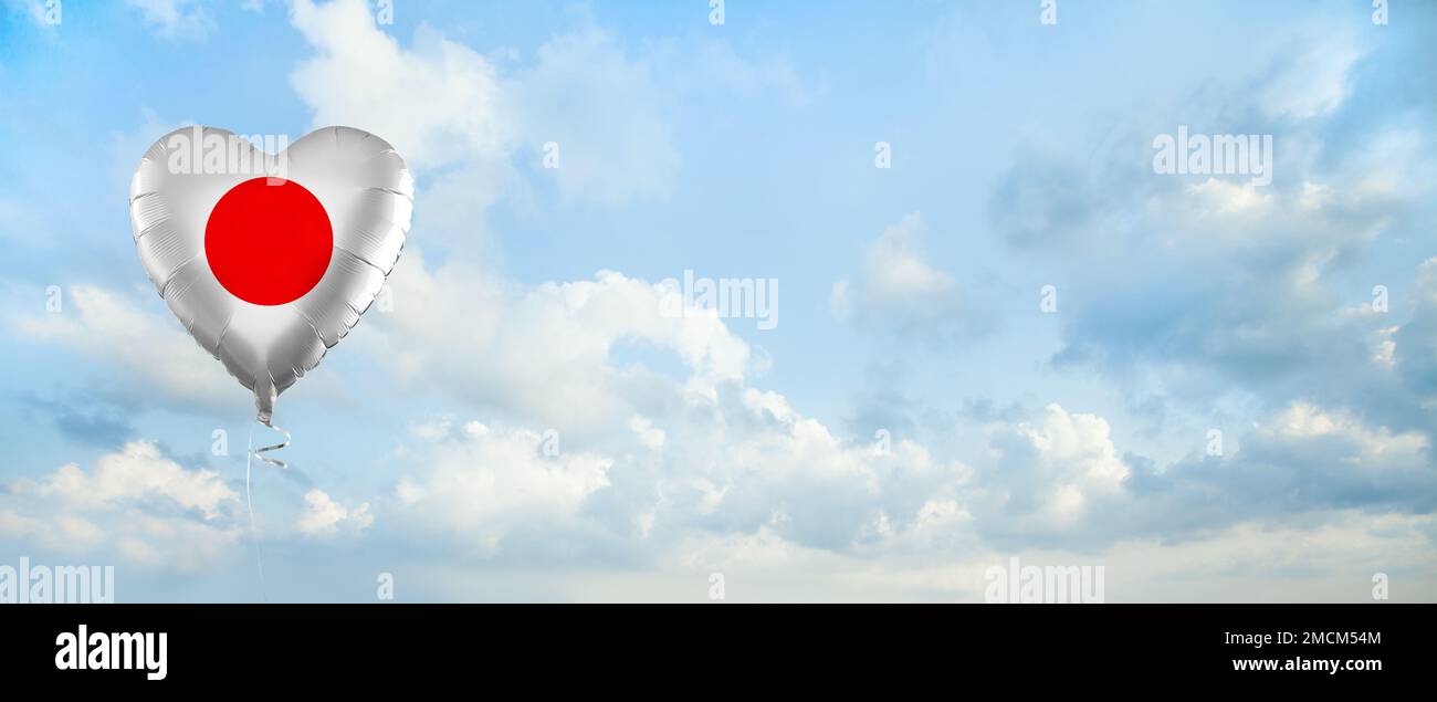 Flag of Japan on heart-shaped balloon against sky clouds background ...