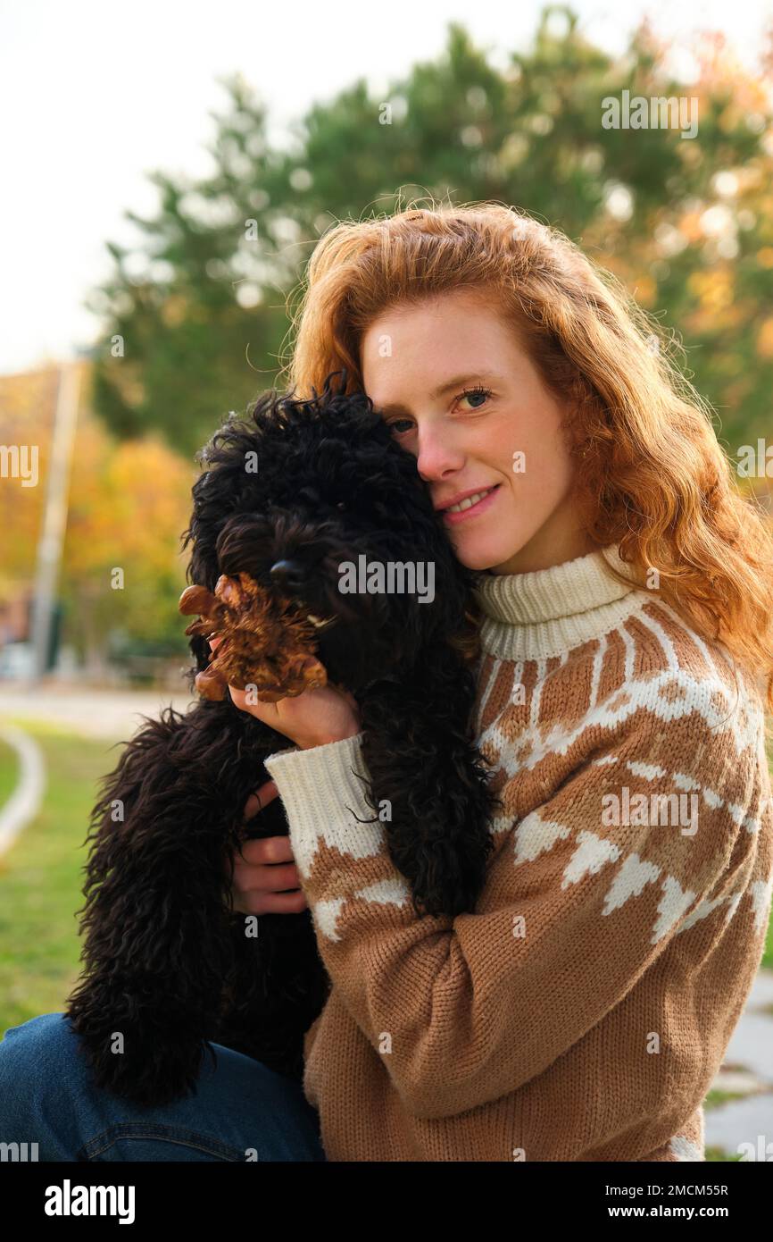 Young woman hugging her black puppy poodle dog in a park Stock Photo ...