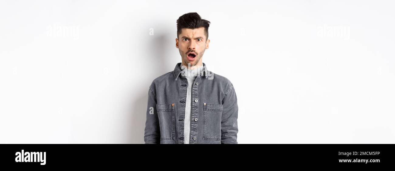 Shocked and offended man frowning, looking at camera with opened mouth ...