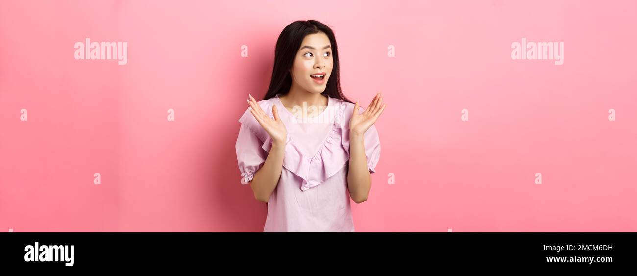 Excited asian girl clap hands and looking left, watching performance ...